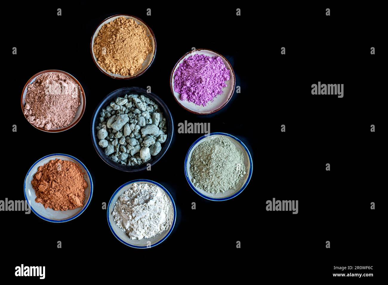 Various types of healing earth in small bowls on a black background ...