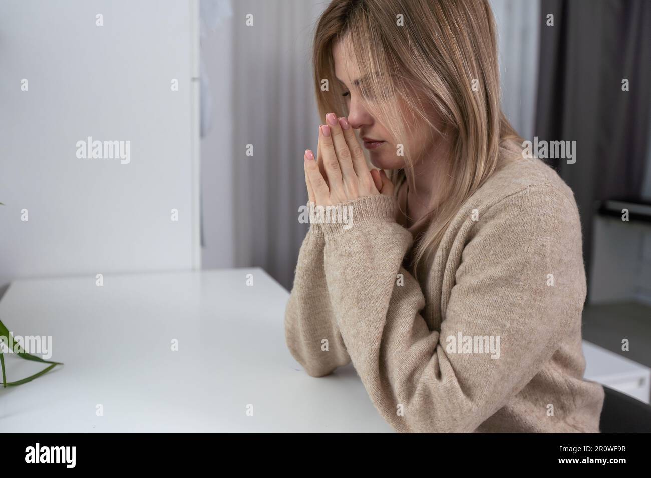 Spirituality and young people. Girl praying at home alone. Worried ...