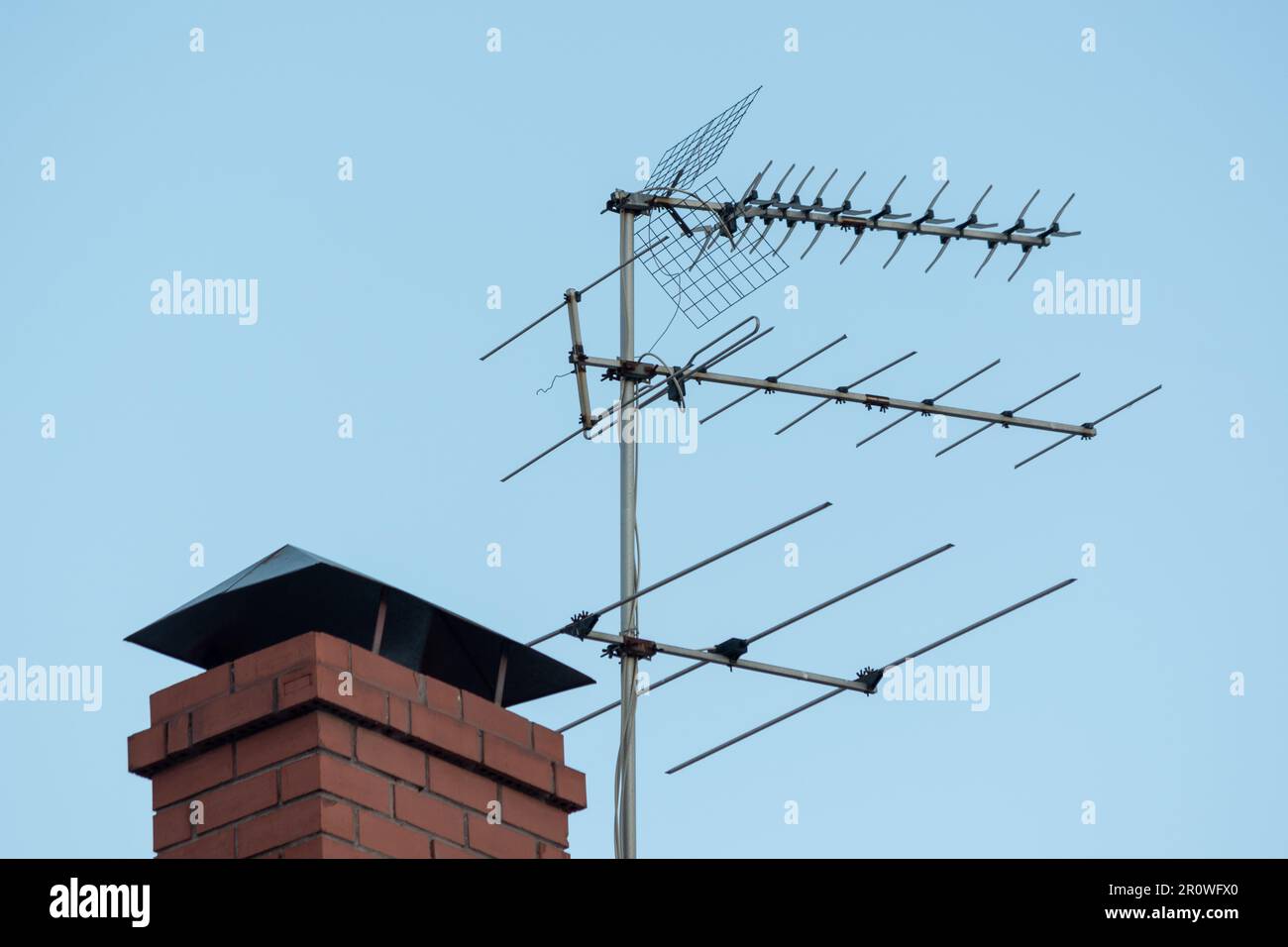 TV antenna on red roof. television antenna on roof with blue sky. Brick pipe house and media ...