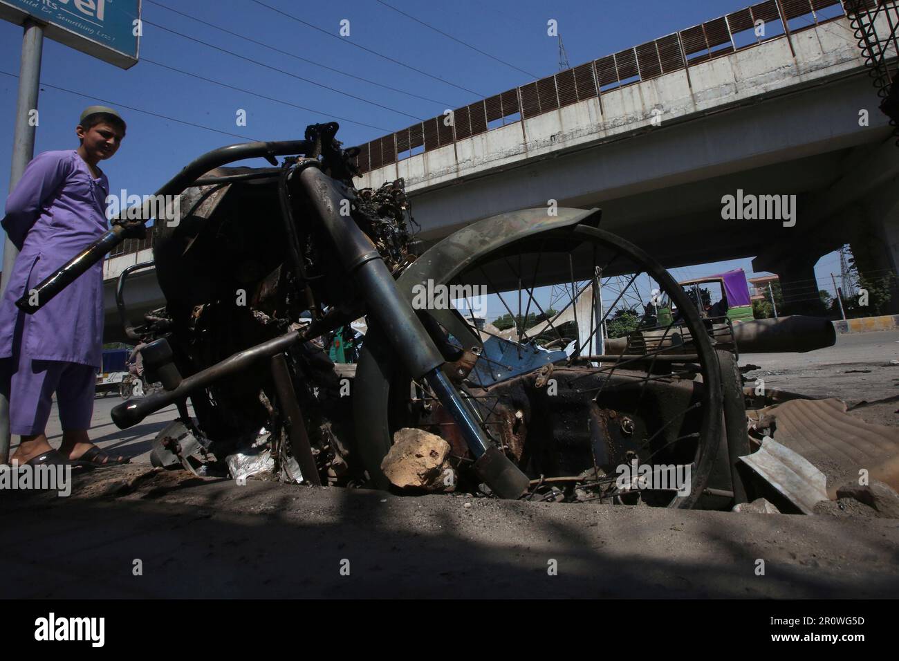 A boy stands near a burnt motorbike on a roadside a day after of ...