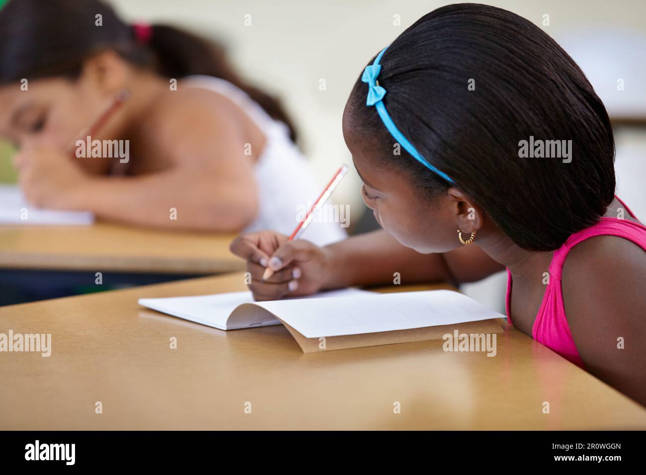 Working hard at school. a young pupil writing in a workbook in a ...