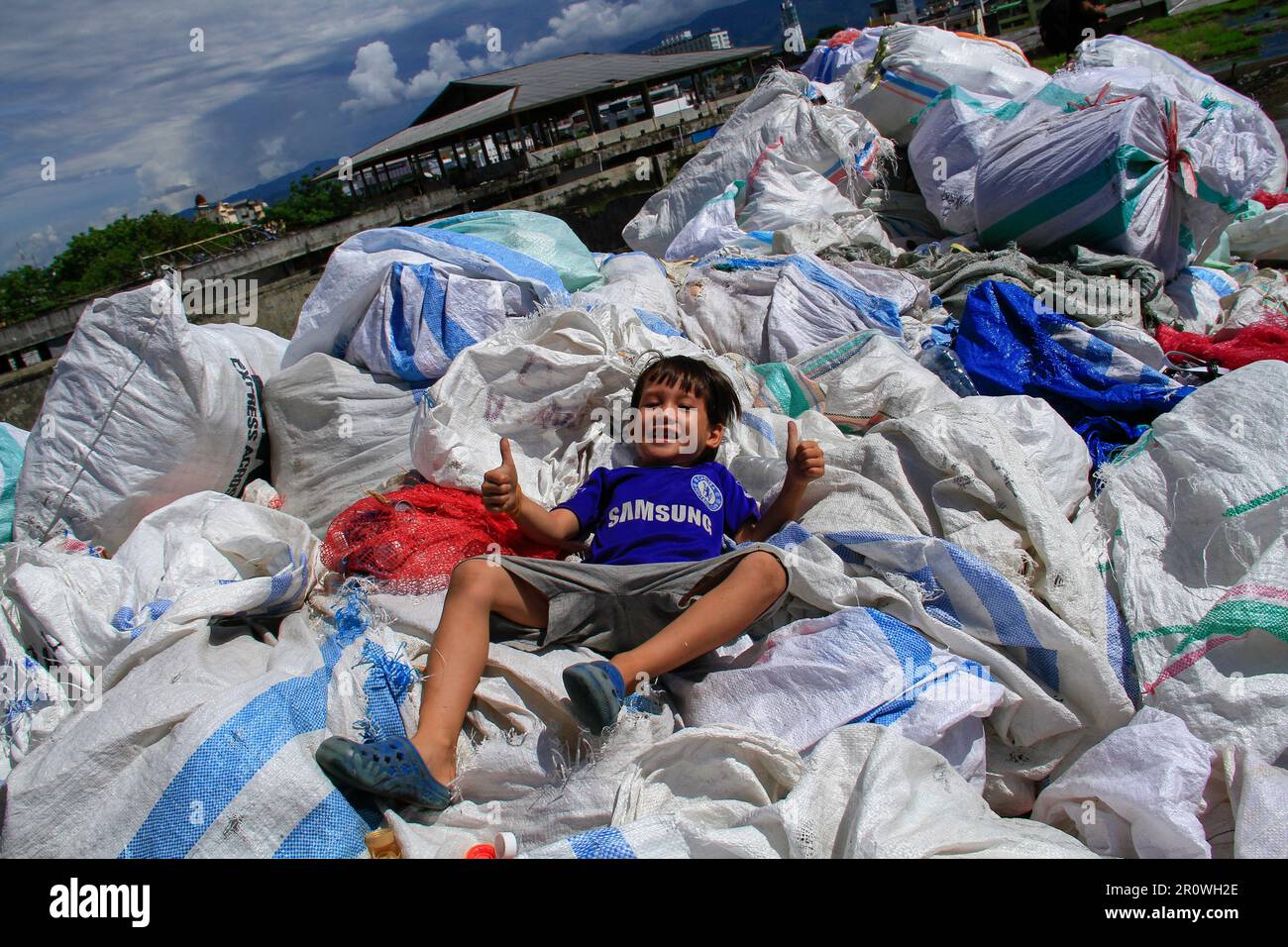Children playing in piles of trash sacks, looking space in the hot sun ...