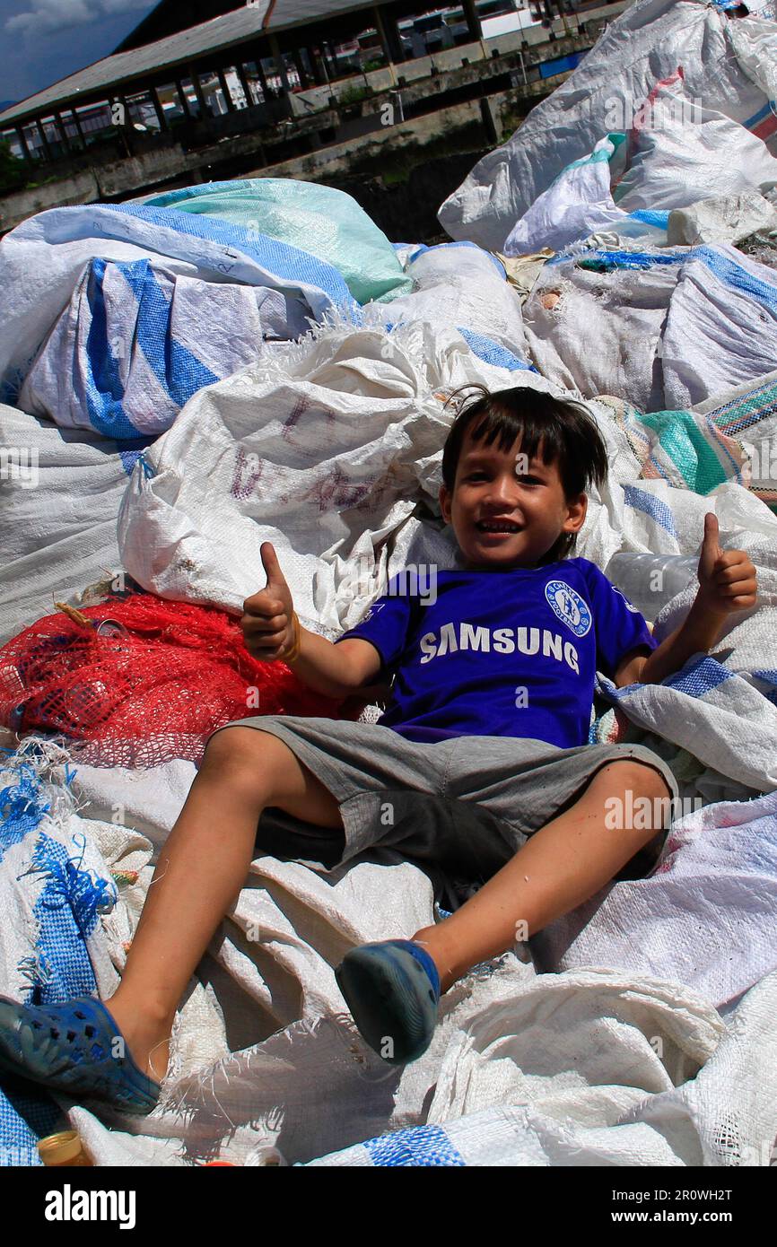 Children playing in piles of trash sacks, looking space in the hot sun ...