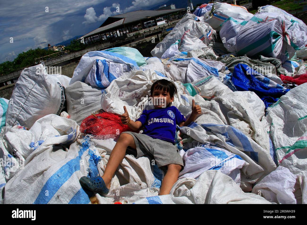 Children playing in piles of trash sacks, looking space in the hot sun ...