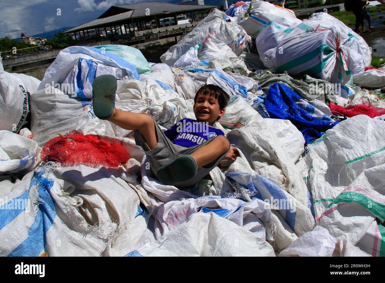 Children playing in piles of trash sacks, looking space in the hot sun ...