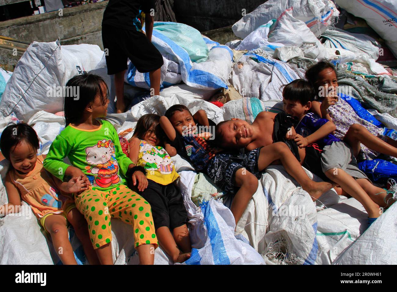 Children playing in piles of trash sacks, looking space in the hot sun ...