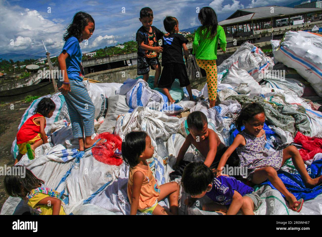 Children playing in piles of trash sacks, looking space in the hot sun ...