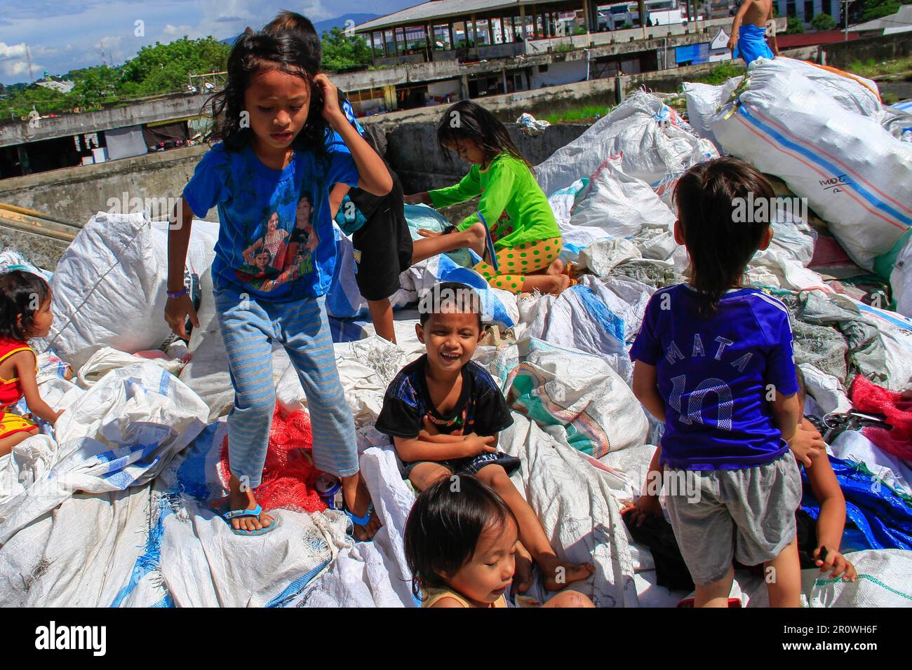 Children playing in piles of trash sacks, looking space in the hot sun ...
