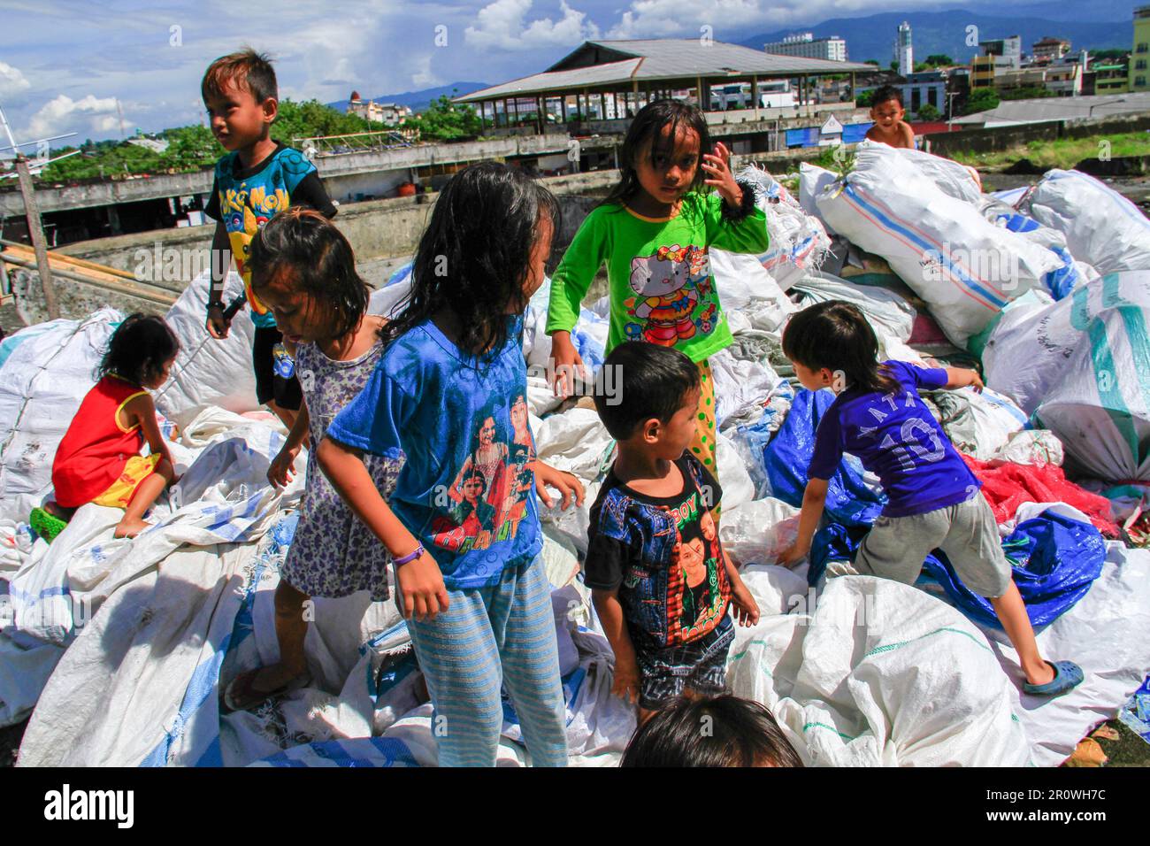 Children playing in piles of trash sacks, looking space in the hot sun ...