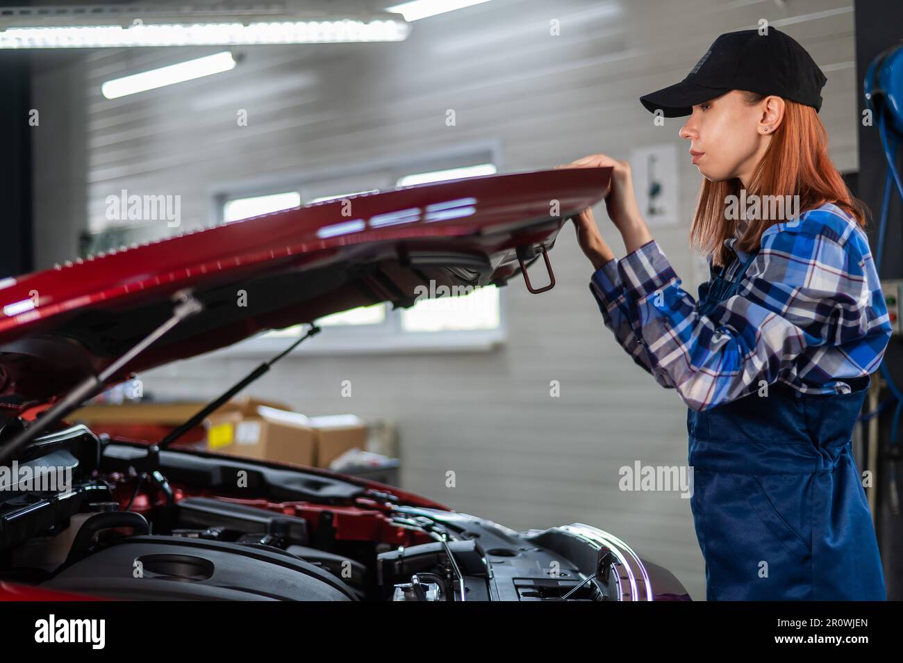 Woman auto mechanic opens the hood of a car in a car service Stock ...