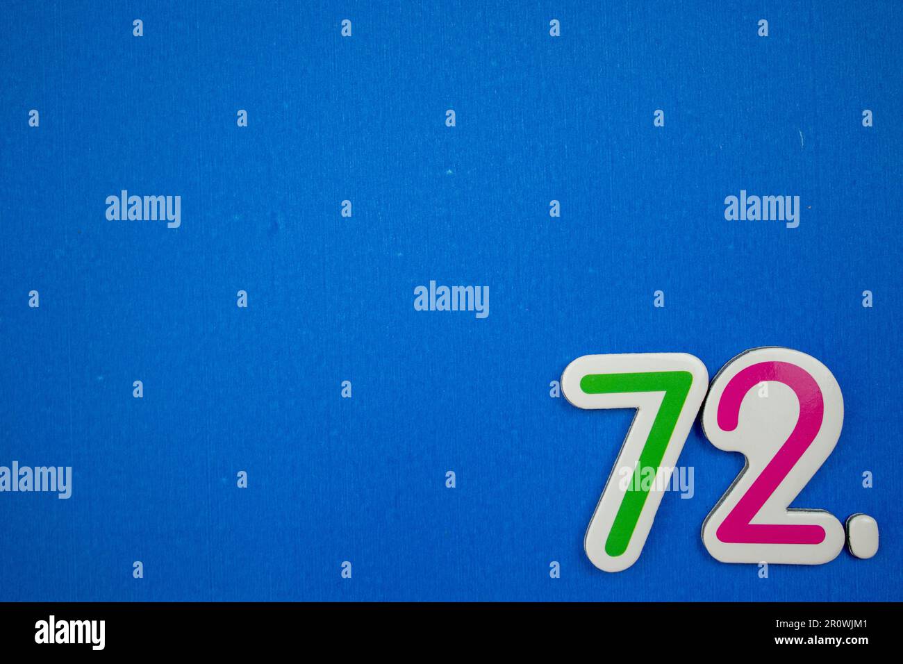 The number 72, placed on the edge of a blue background, photographed ...