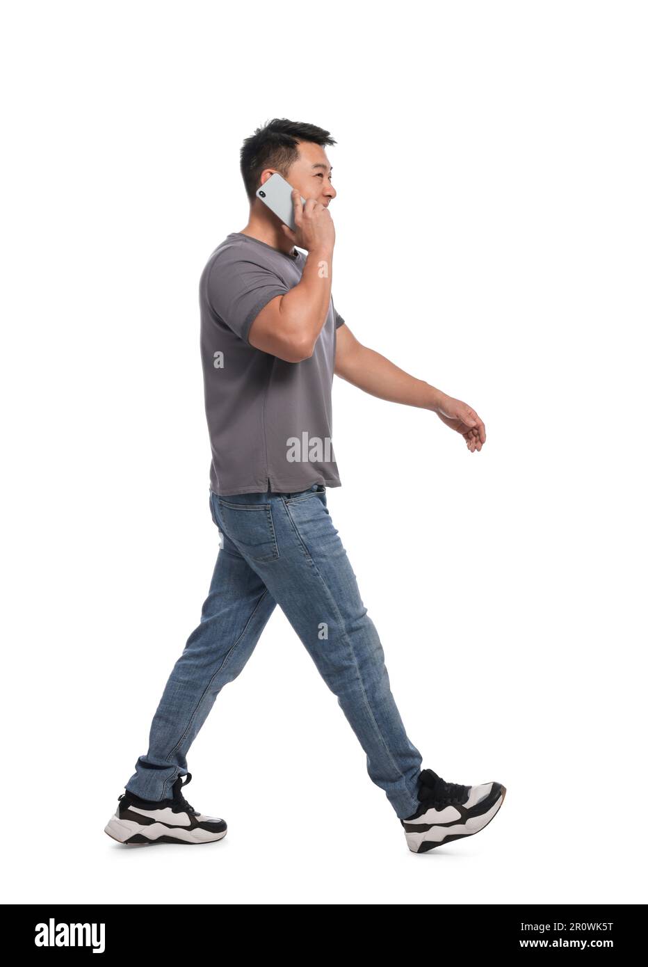 Man talking on smartphone while walking against white background Stock ...
