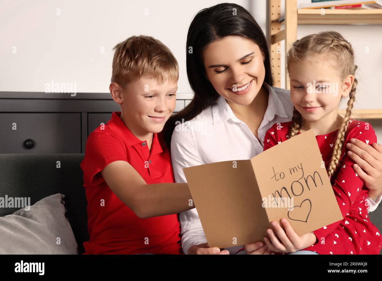 Happy woman receiving greeting card from her children at home Stock ...