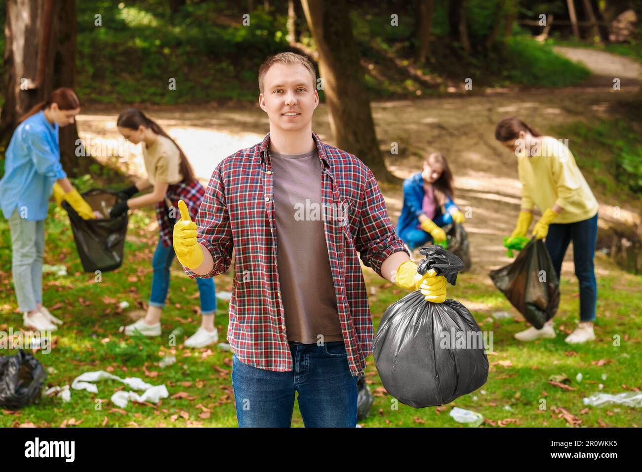 Young man with plastic bag showing thumb up and group of people ...