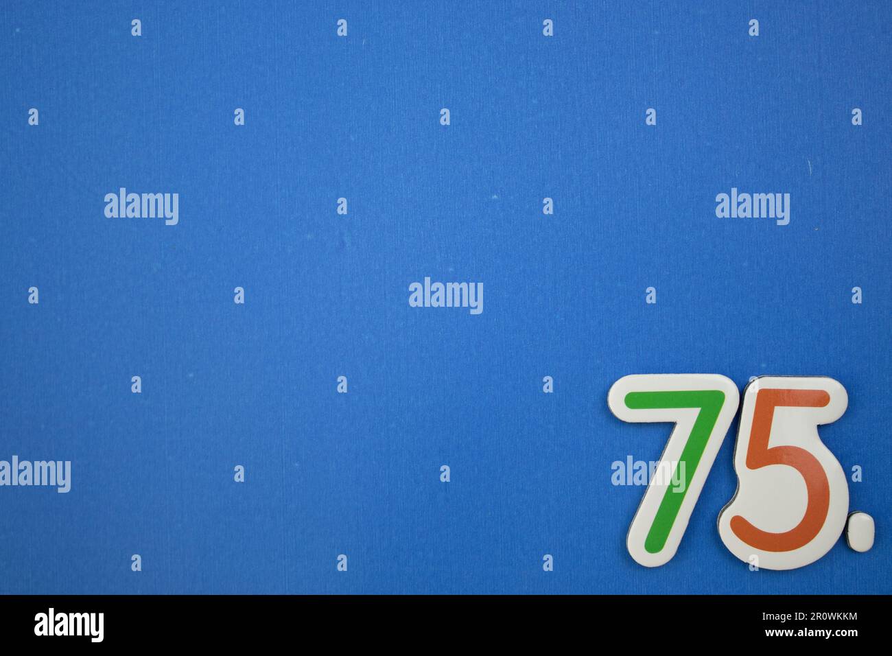 The number 75, placed on the edge of a blue background, photographed ...
