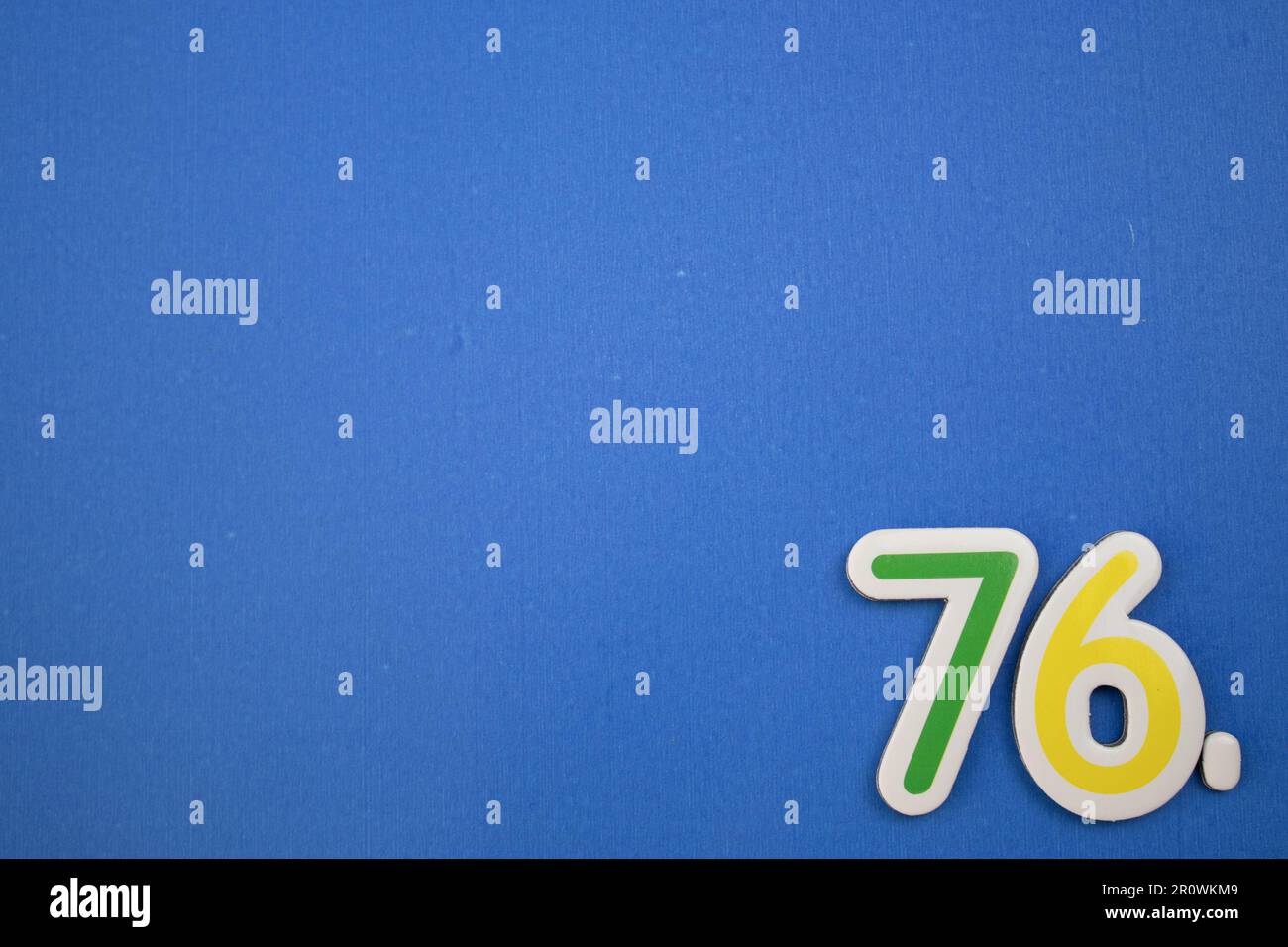 The number 76, placed on the edge of a blue background, photographed ...