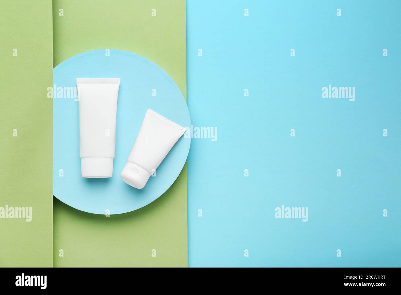 Tubes of hand cream on turquoise background, flat lay. Space for text ...
