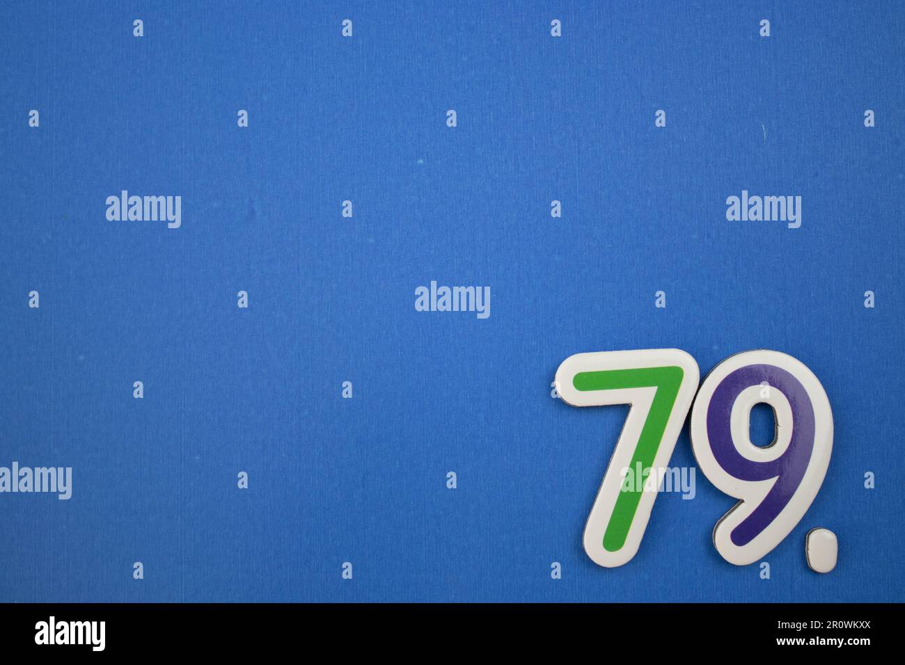 The number 79, placed on the edge of a blue background, photographed ...