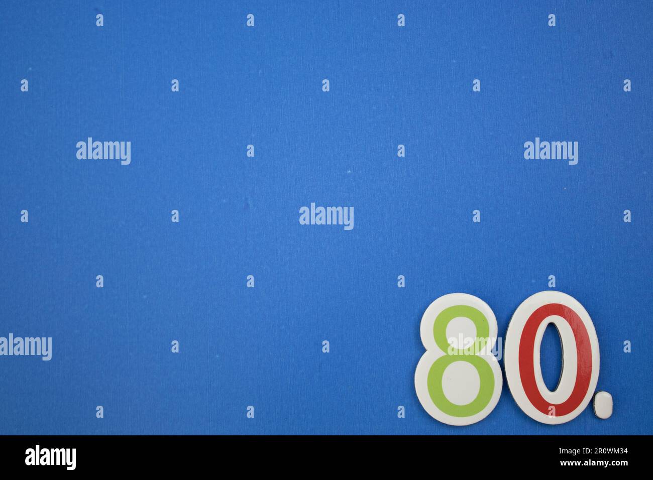 The number 80, placed on the edge of a blue background, photographed ...