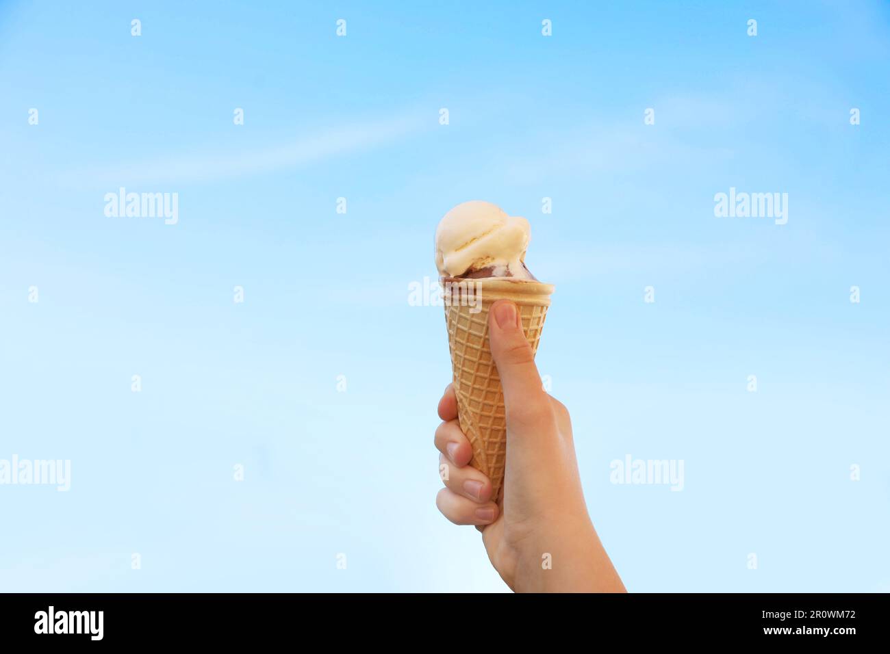 Woman holding waffle cone with delicious ice cream against blue sky on ...