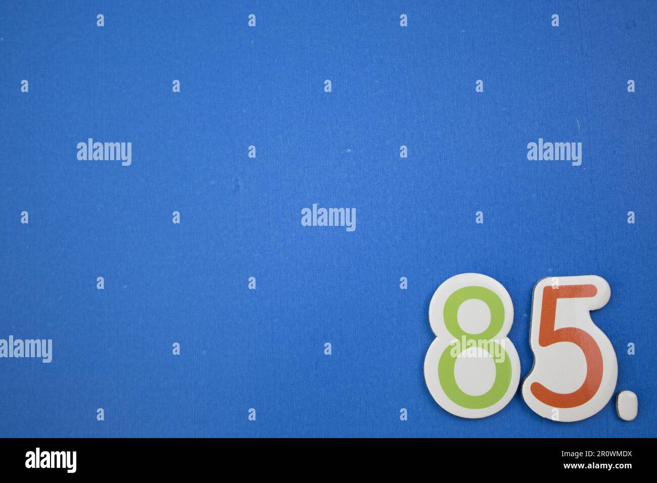 The number 85, placed on the edge of a blue background, photographed ...
