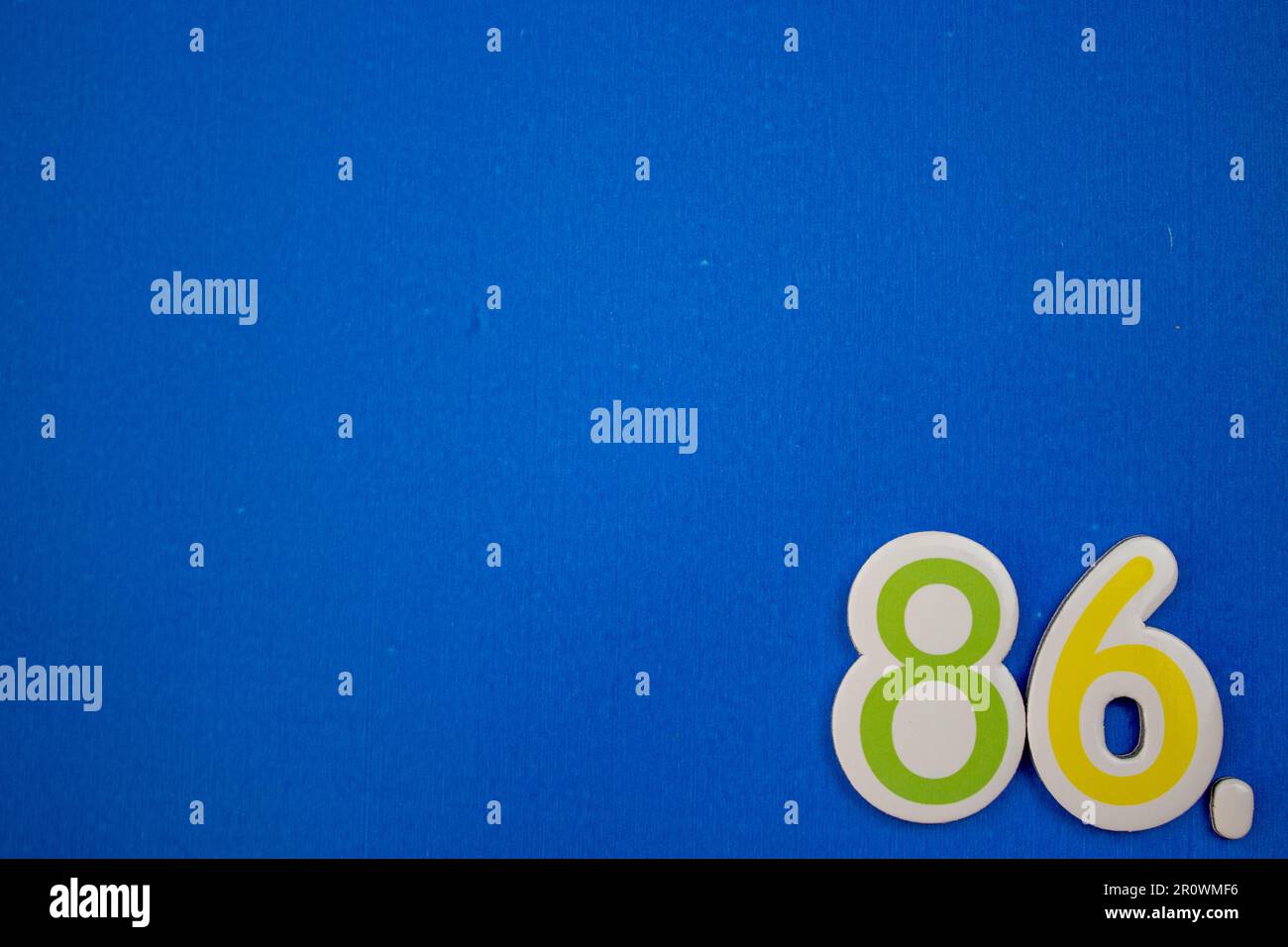 The number 86, placed on the edge of a blue background, photographed ...