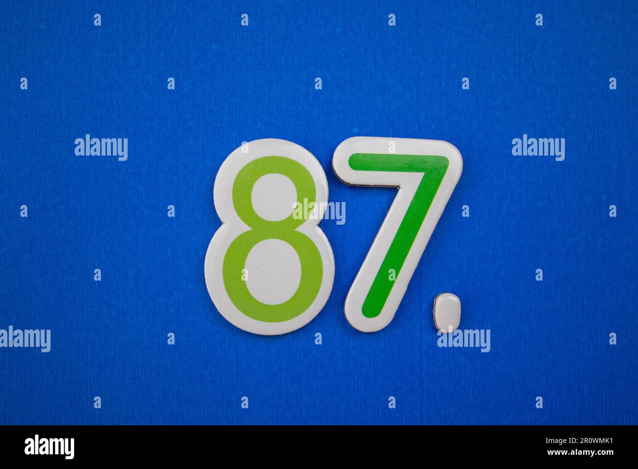 The number 87, placed on a blue background, photographed from above, in ...