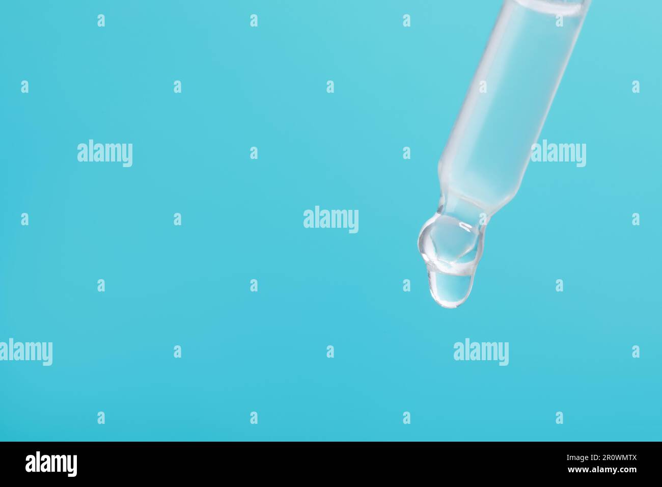 Dripping serum from pipette on light blue background, closeup. Space ...