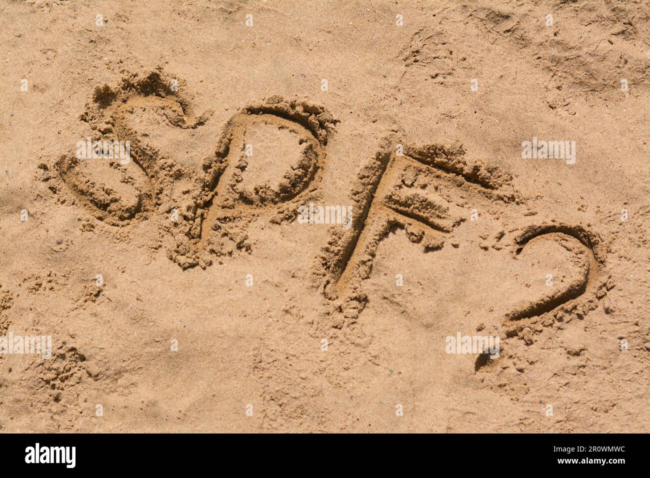 Abbreviation SPF and question mark written on sand at beach, above view ...