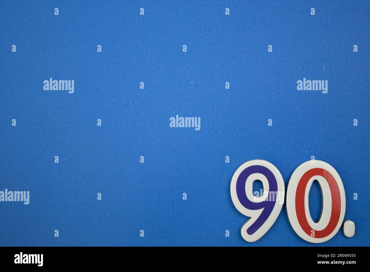 The number 90, placed on the edge of a blue background, photographed ...