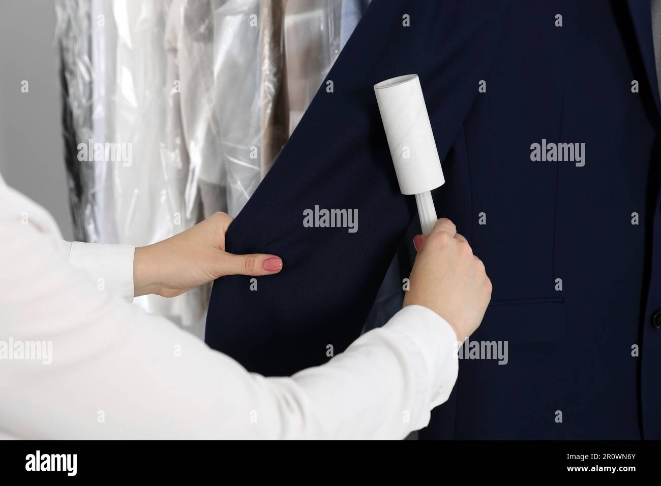 Woman using adhesive lint roller indoors, closeup. Dry-cleaning service ...