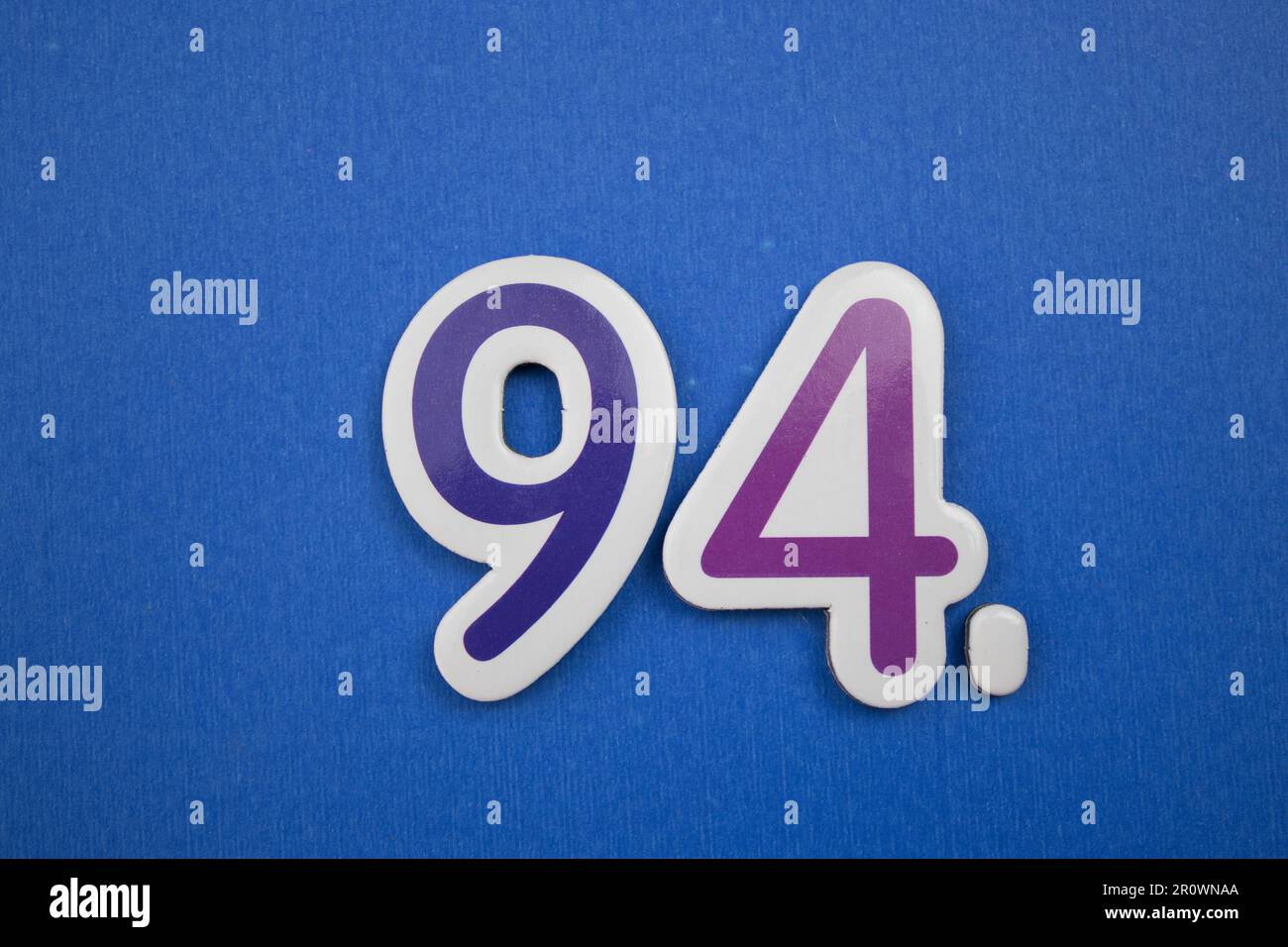 The number 94, placed on a blue background, photographed from above, colored blue and purple ...