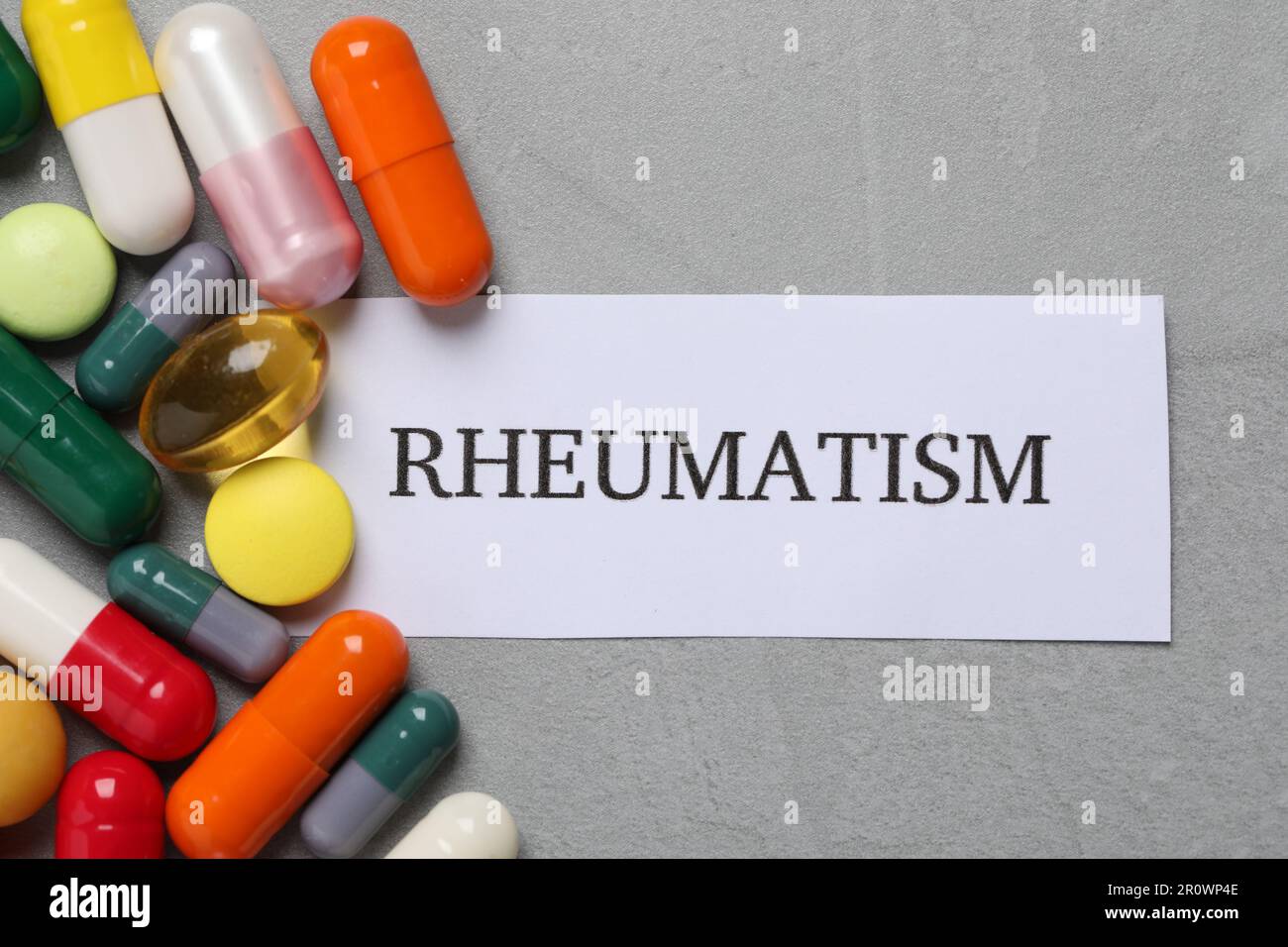 Sheet of paper with word Rheumatism and many different pills on light ...