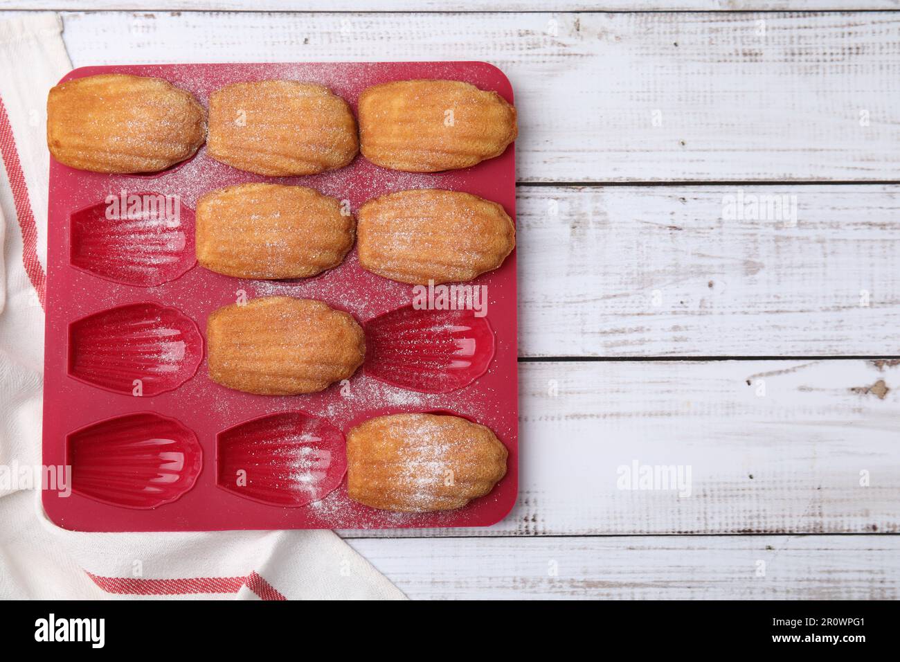 Delicious madeleine cookies in baking mold on white wooden table, top ...
