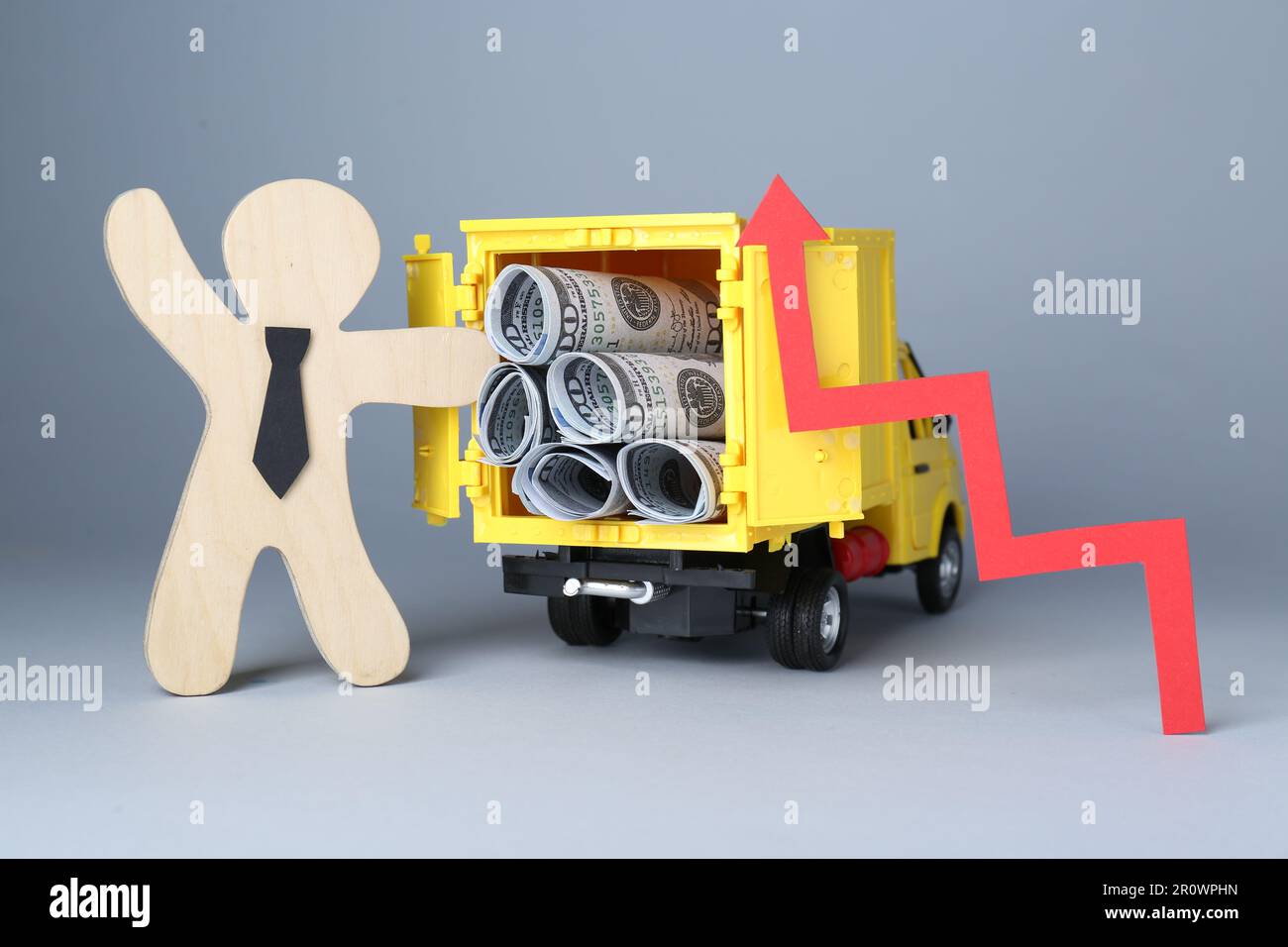 Economic profit. Wooden figure, arrow and toy truck with banknotes on ...