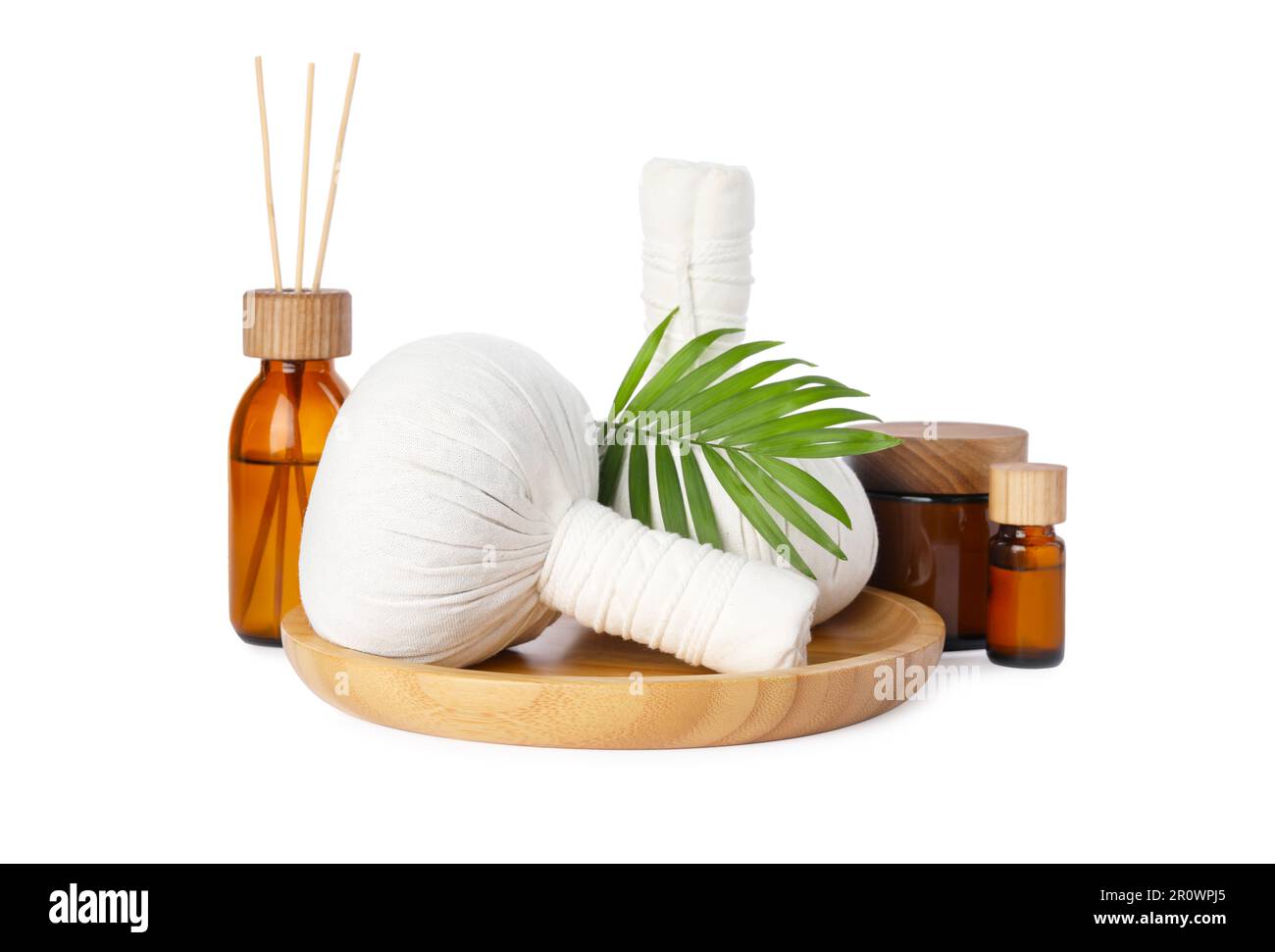 Wooden tray with herbal massage bags and different spa products on ...