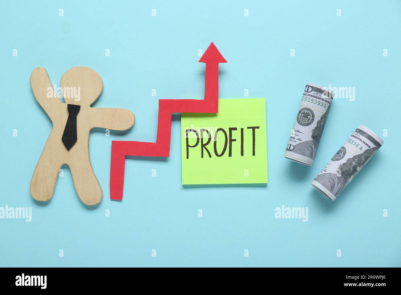 Sticky note with word Profit, rolled banknotes, up arrow and wooden ...