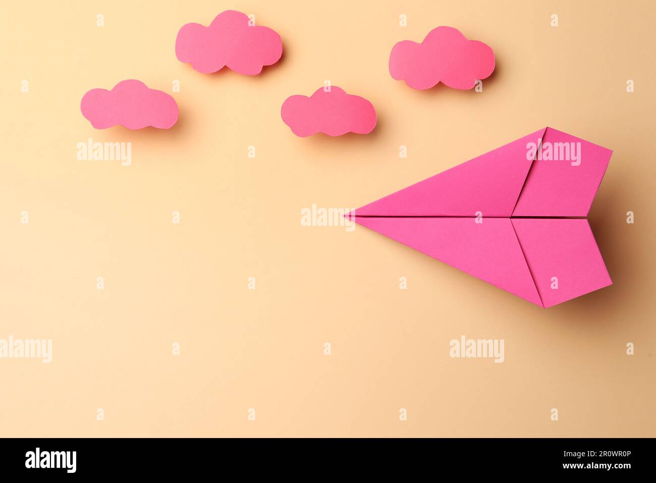 Handmade pink paper plane with clouds on beige background, flat lay ...