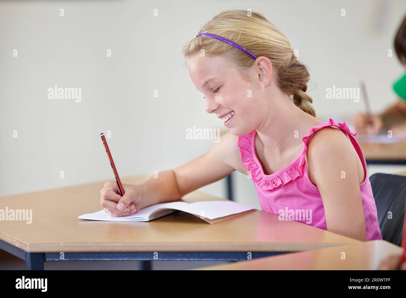 Working hard at school. a young pupil writing in a workbook in a ...