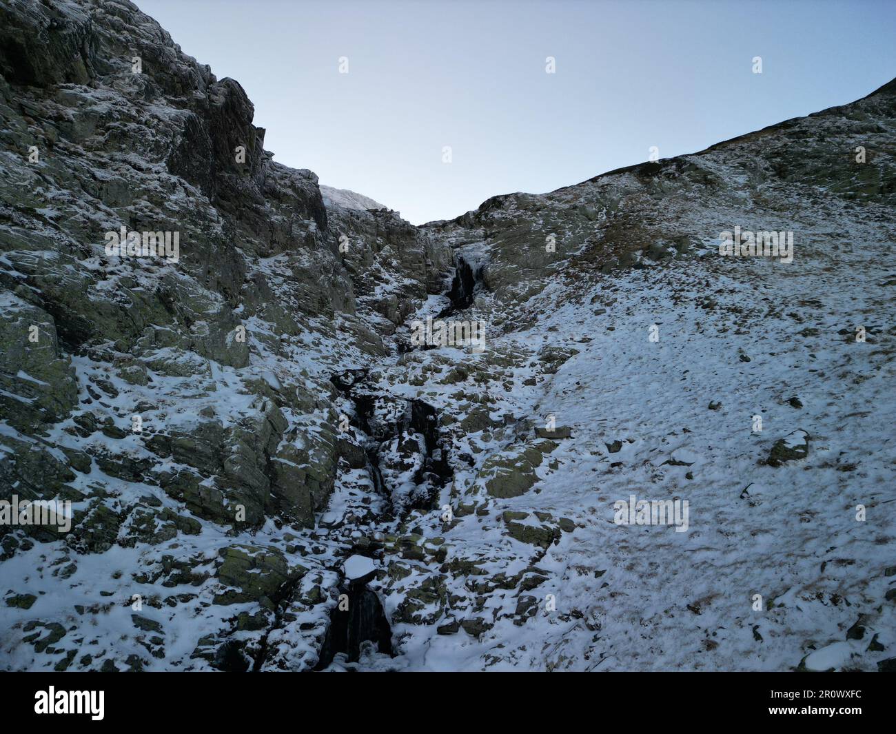A white winter scene of a snow-covered hillside, dotted with rocks ...