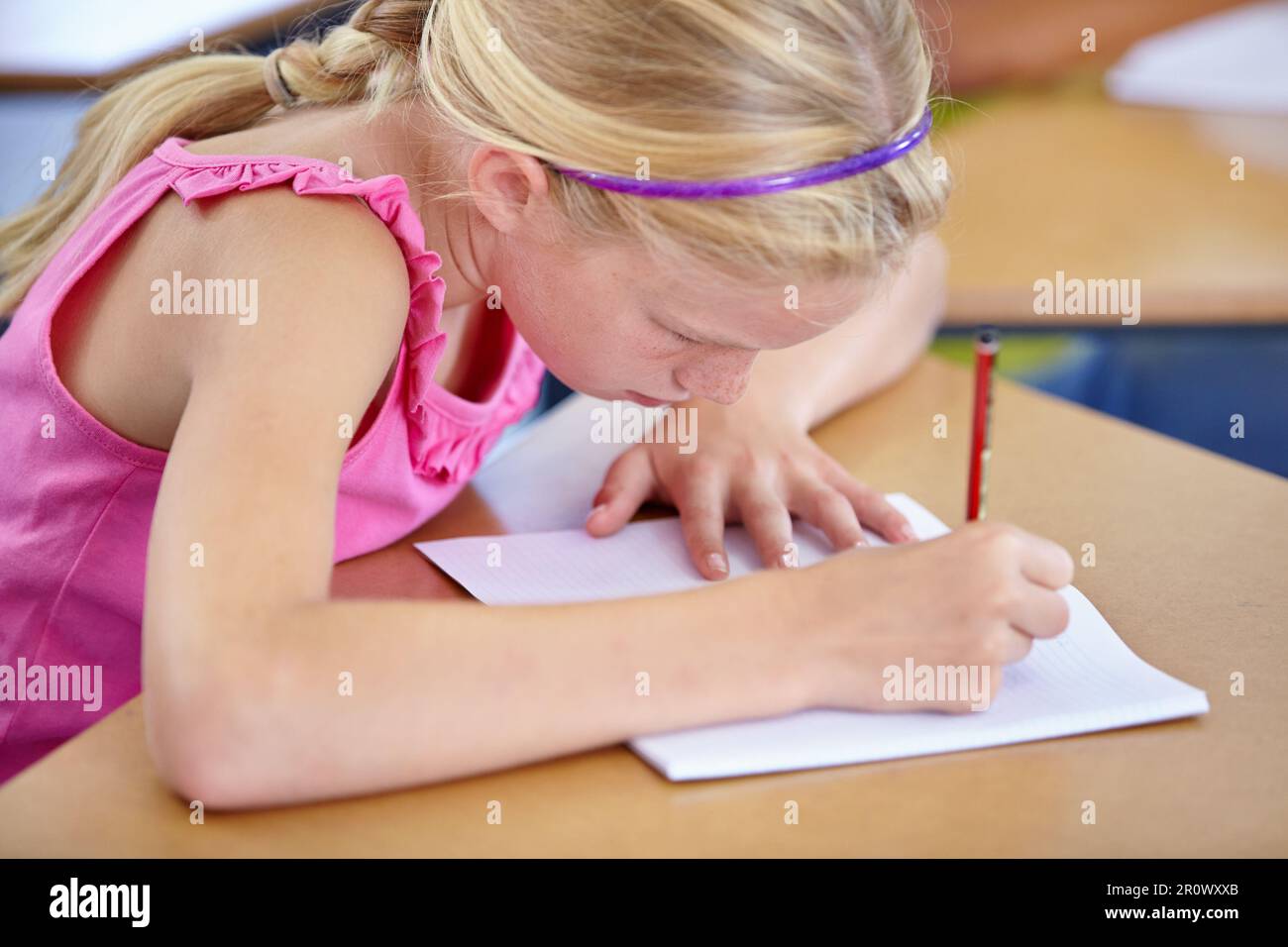 Working hard at school. a young pupil writing in a workbook in a ...