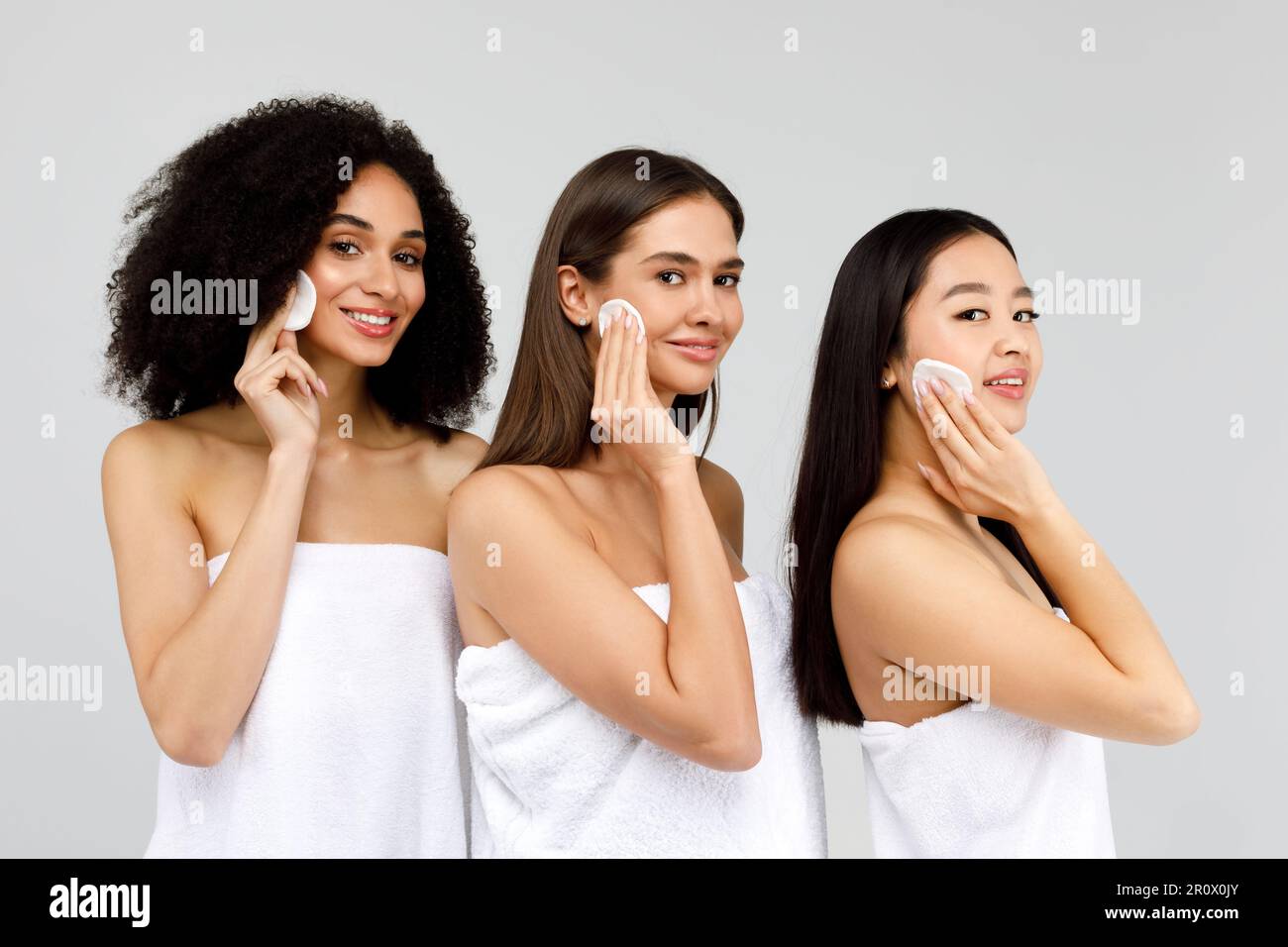 Facial skincare concept. Young three diverse ladies in towels using ...