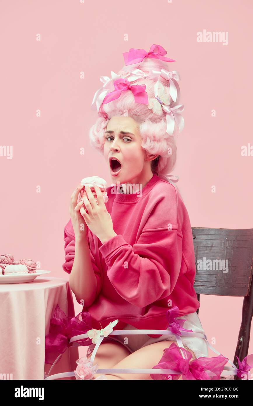 Portrait hungry queen wearing big pink wig eating marshmallow with ...
