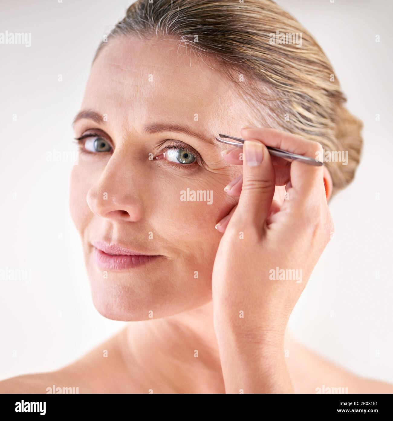 Tending to her eyebrows. Cropped portrait of a mature woman plucking ...