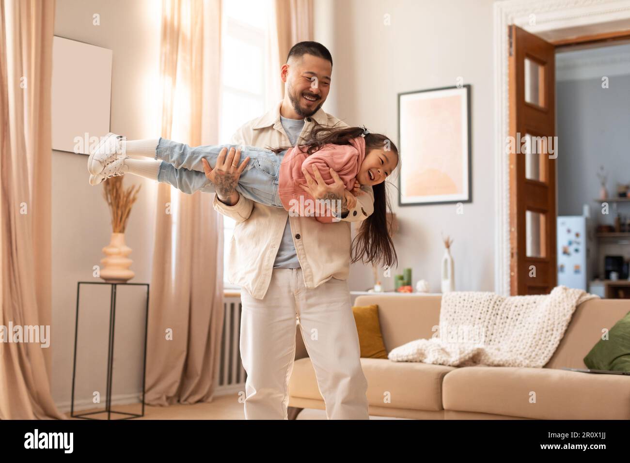 Happy Japanese Dad Lifting Little Daughter Enjoying Playtime At Home ...