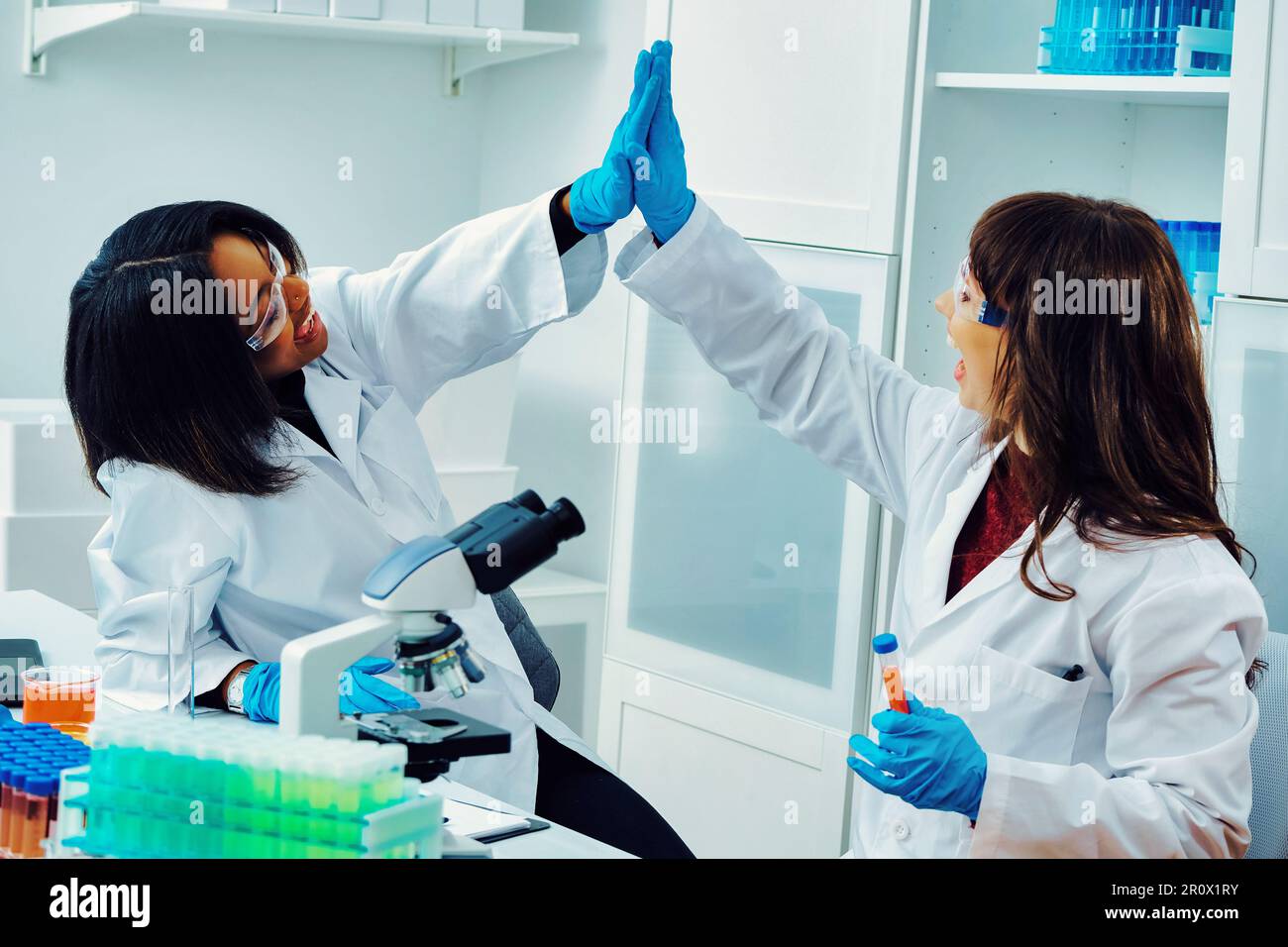 Two young women wearing lab coats giving each other high five Stock ...