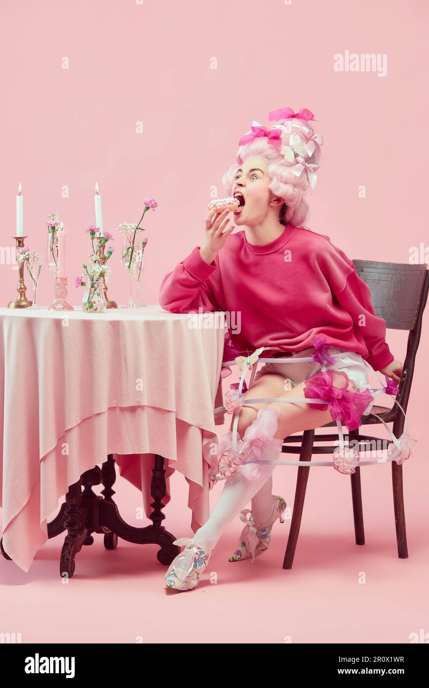 Portrait hungry princess, queen wearing big pink wig eating donut with ...