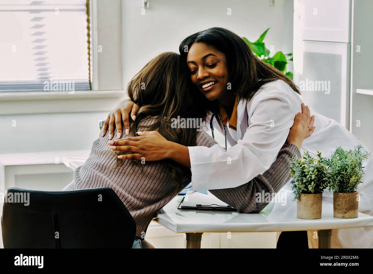 Young black female doctor hugging female patient in surgery, smiling ...