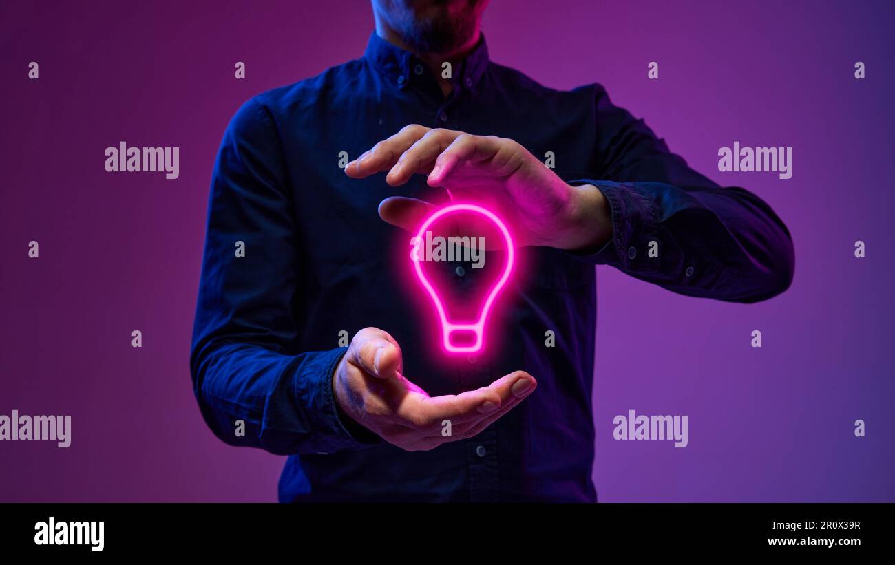 Neon colored light bulb between male hands. Businessman generating ...
