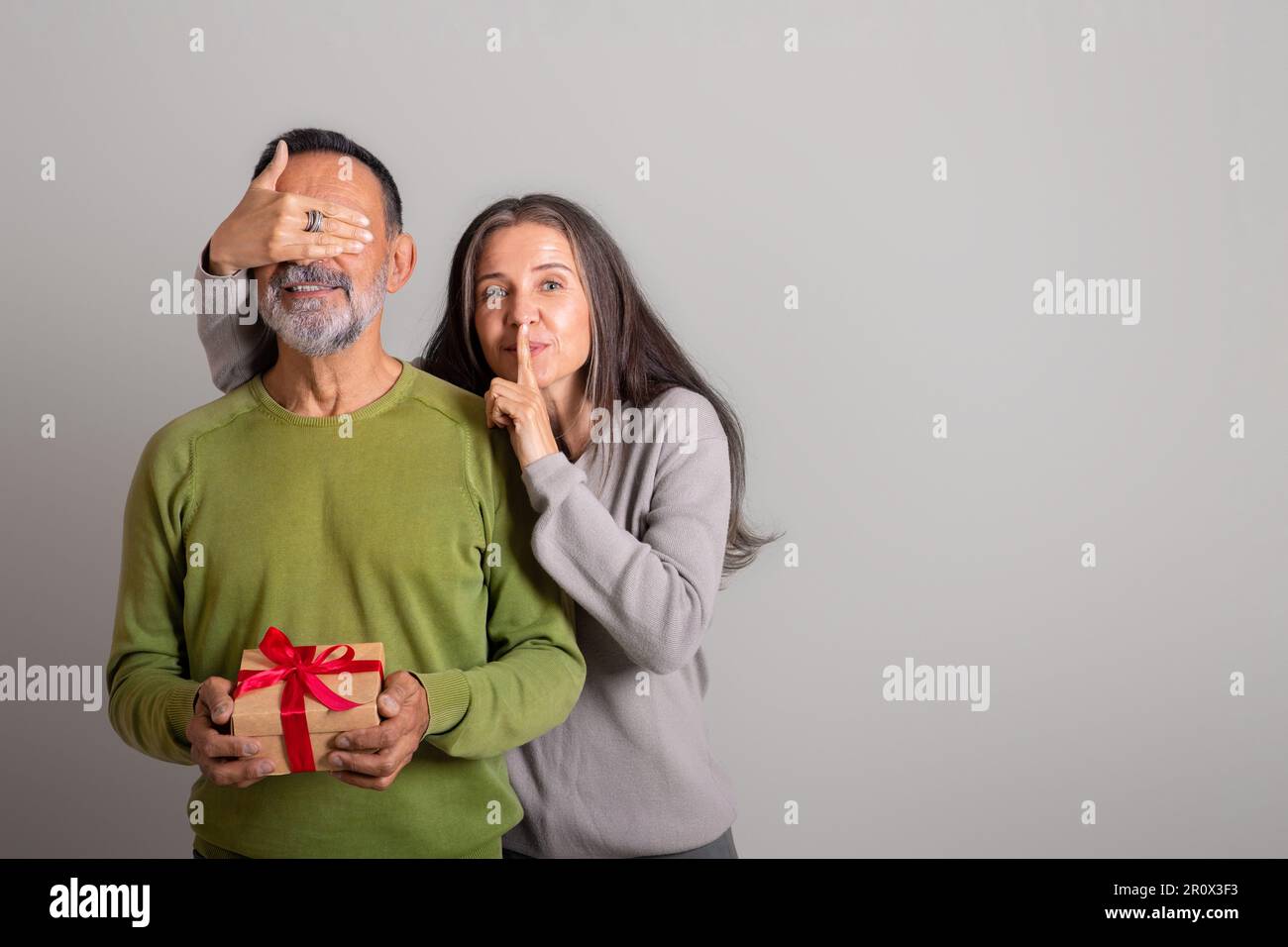 Glad caucasian elderly lady closes eyes to husband, make shh sign ...